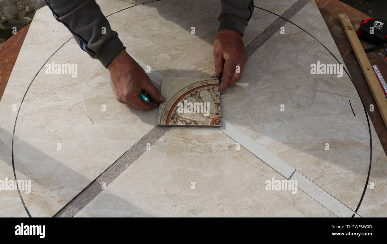 The tiler's hands place a square piece of material with a floral ...
