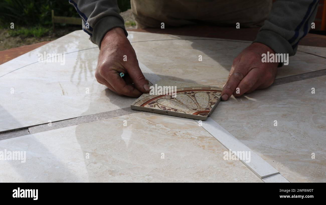 male hands lay out a square tile with a pattern in the middle of a ...