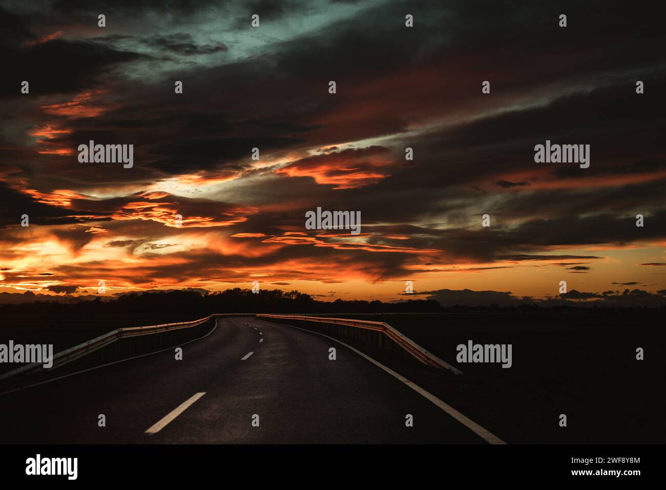 A dark road ahead at evenign time sunset. Cloudy sky in holden hour ...