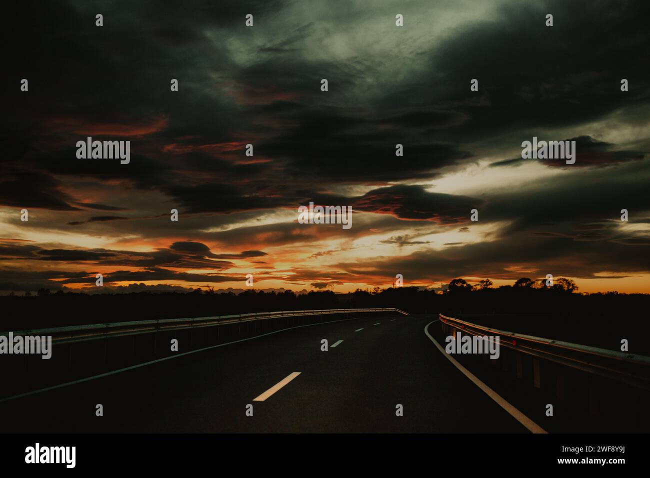 A dark road ahead at evenign time sunset. Cloudy sky in holden hour ...