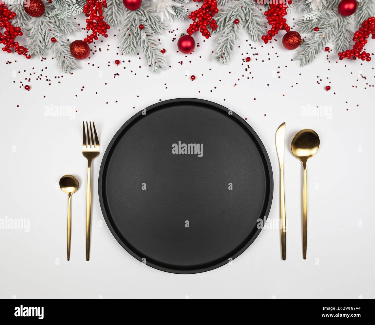 Christmas composition, black plate and gold cutlery, fir tree branches ...