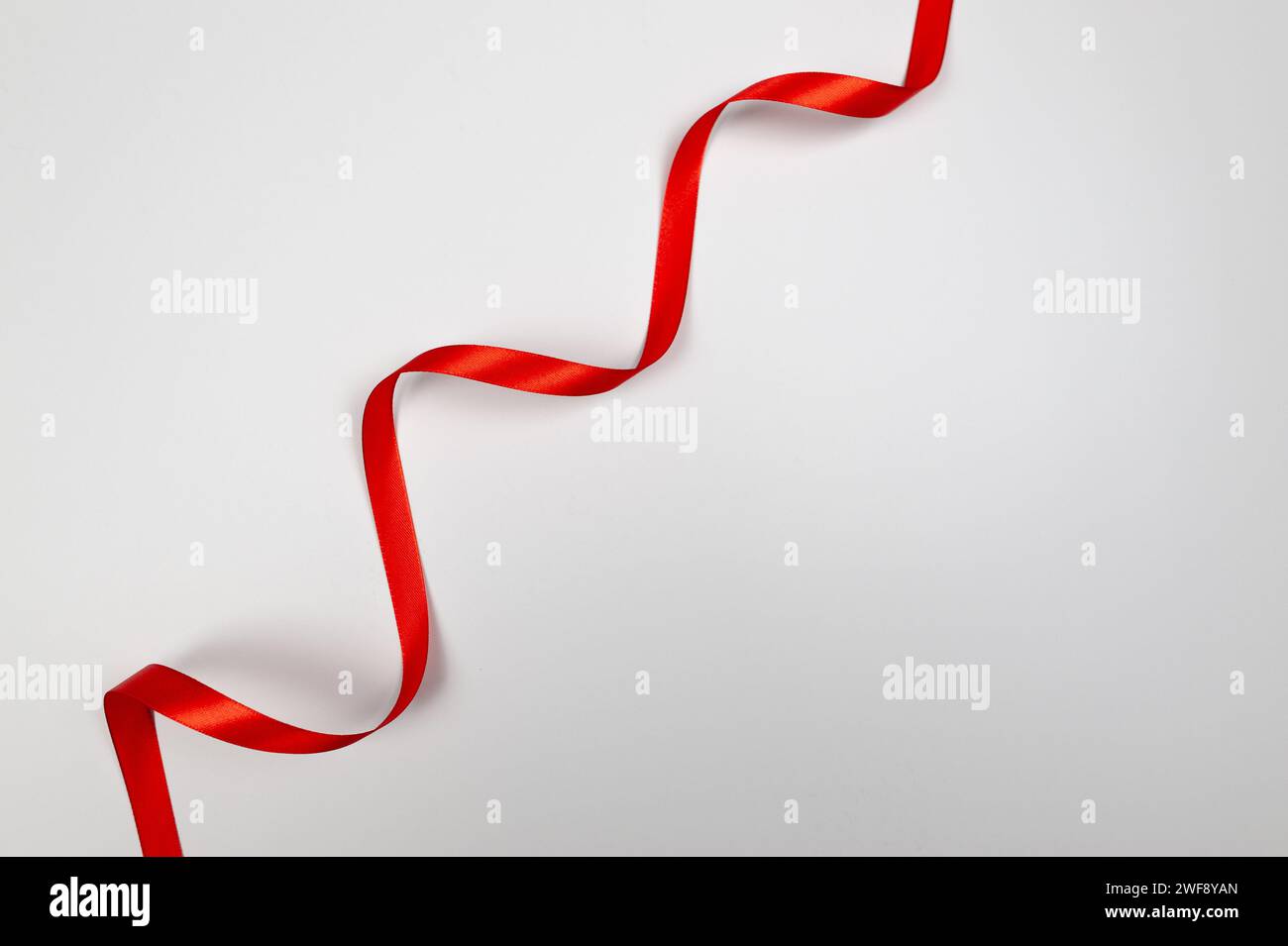 Top view of red ribbon on white background. Shiny rolled fabric, silk ...