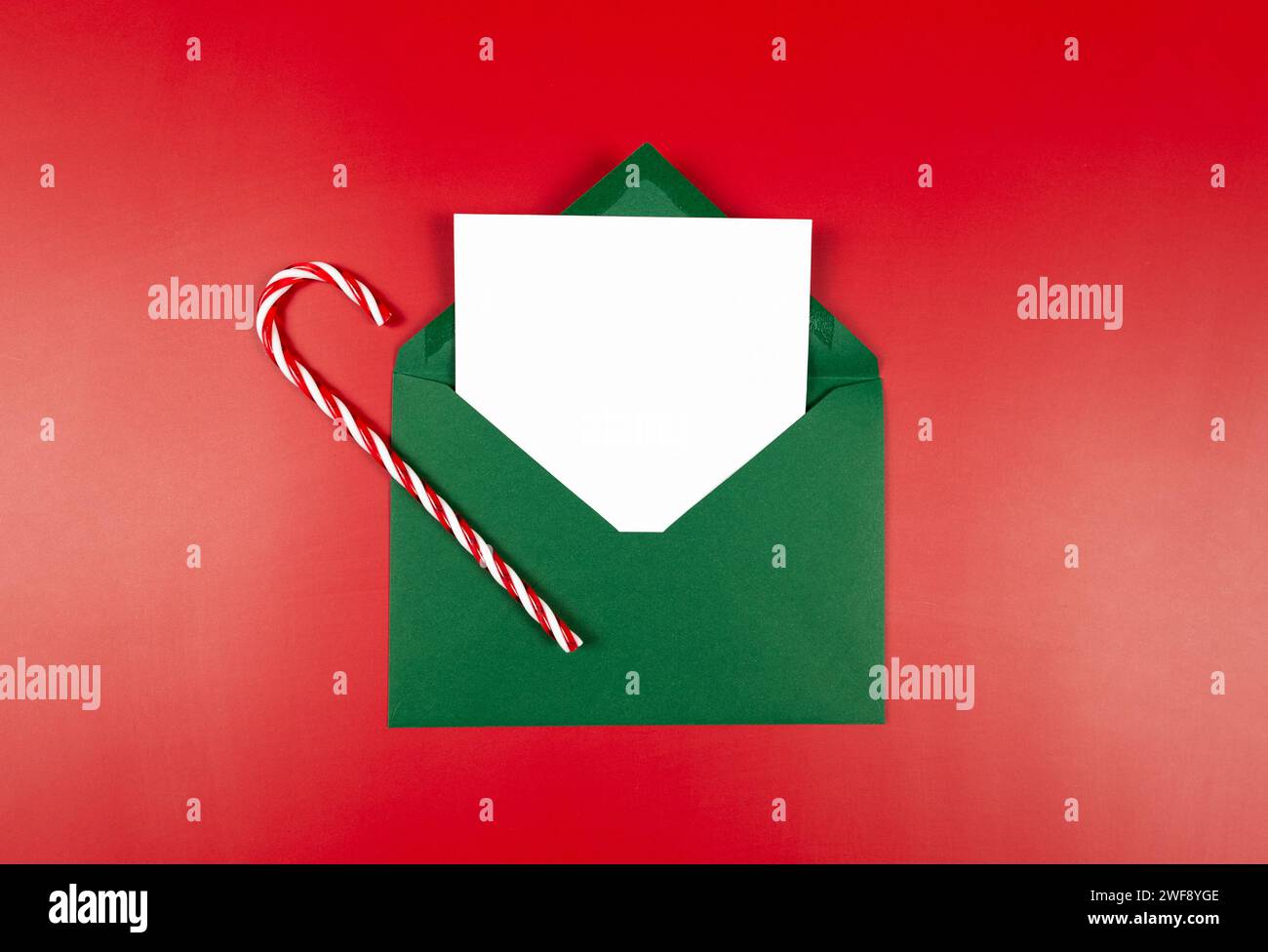 Top view of green envelope, white card and candy canes on red ...