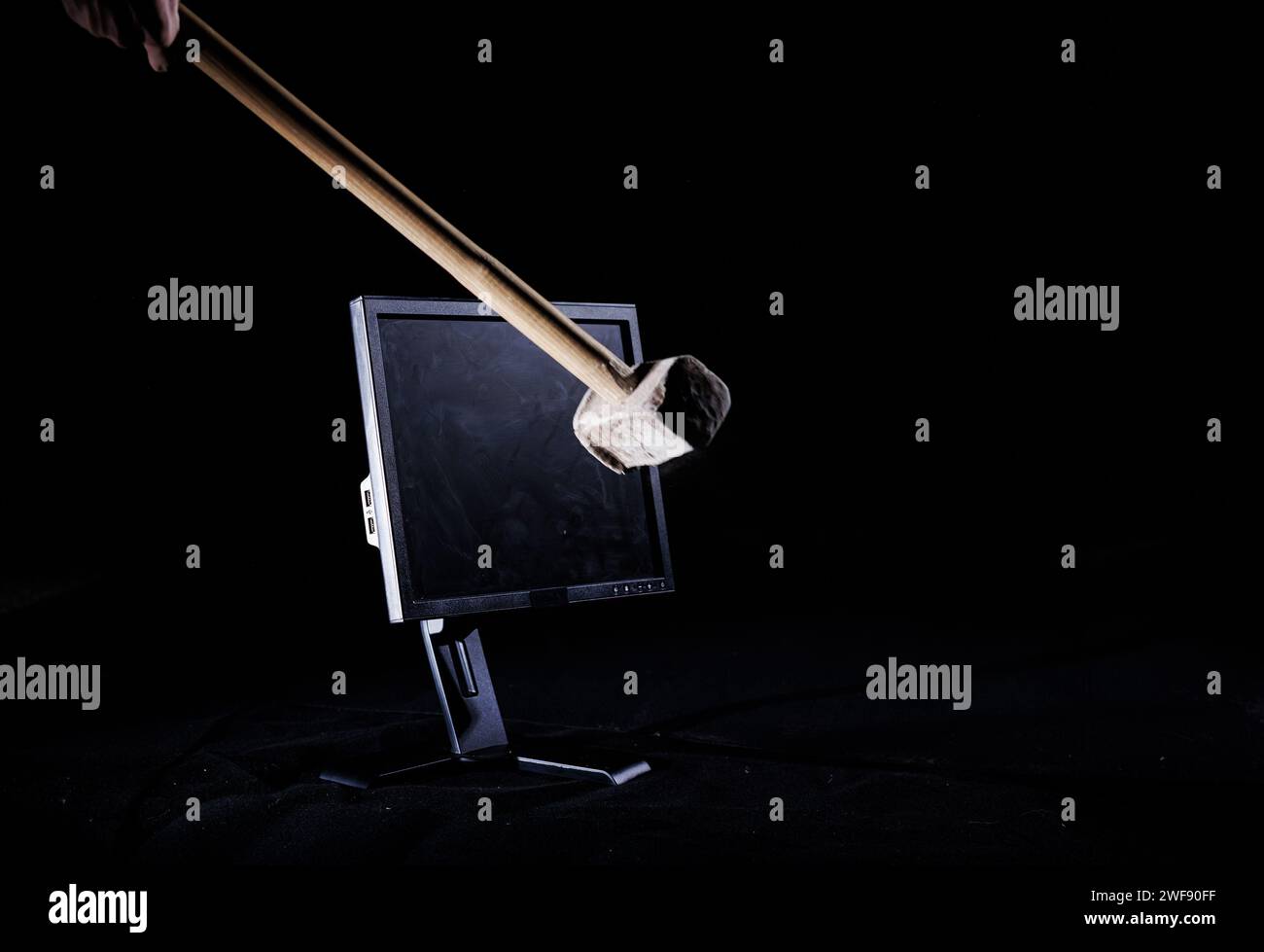 Hand holding a big hammer, hitting and smashing a computer display ...