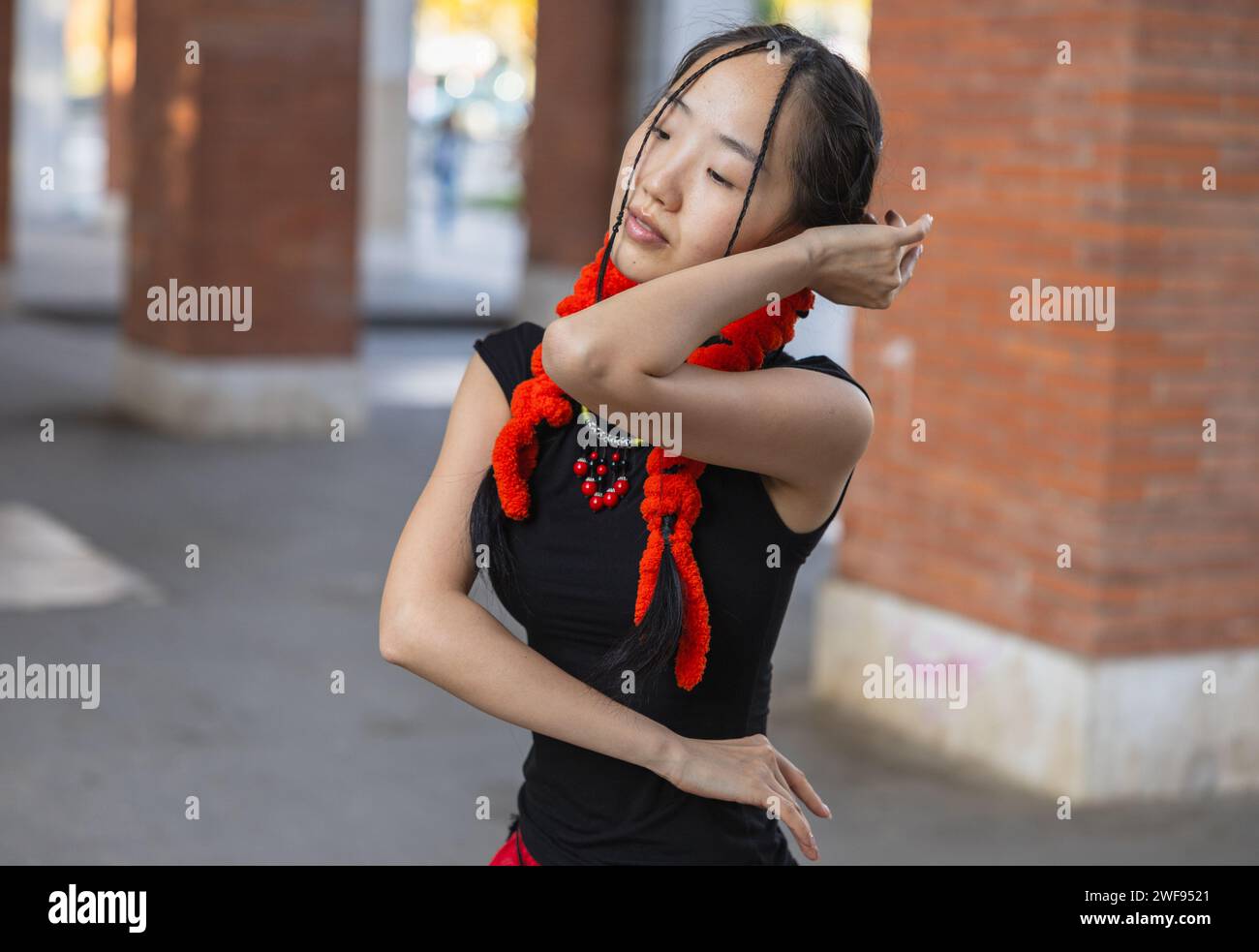 A focused urban dancer warms up with arm stretches, wearing a striking ...