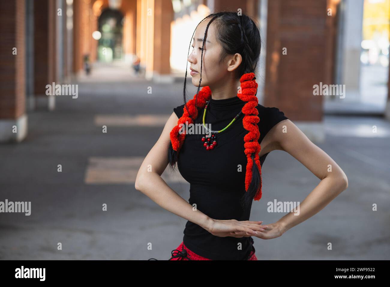 An urban dancer with a bold red scarf finds her center in a moment of ...