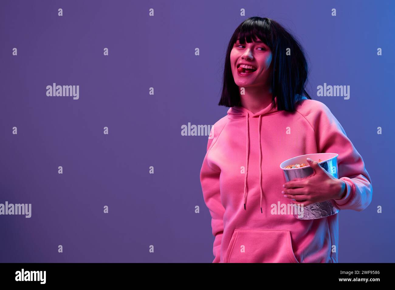 Funny awesome brunet woman in pink hoodie with popcorn show tongue look ...