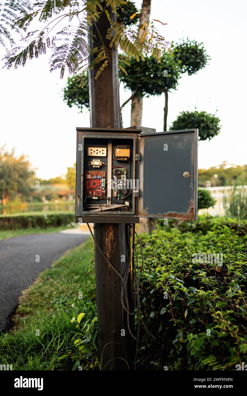 A red wire box is securely fastened to a metal telephone pole, blending ...