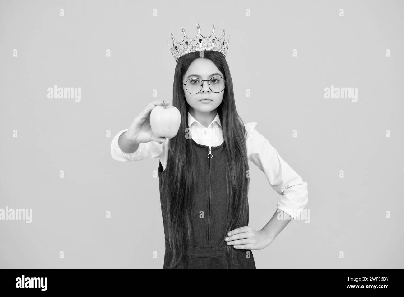 Teen child in queen crown hold apple isolated on yellow background ...