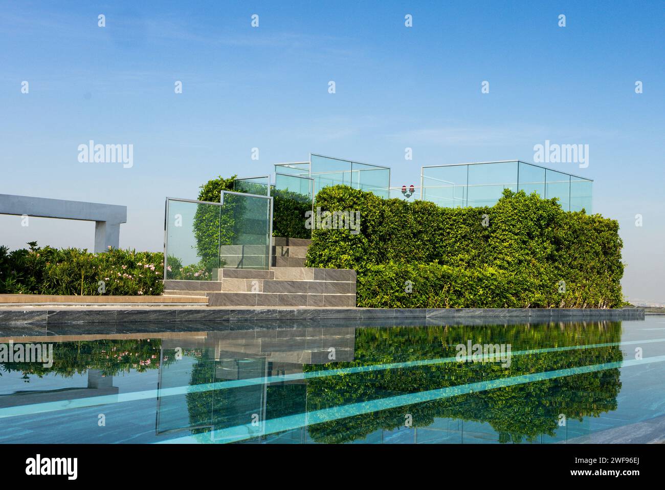 A large pool with a transparent glass fence, nestled in a luxurious ...