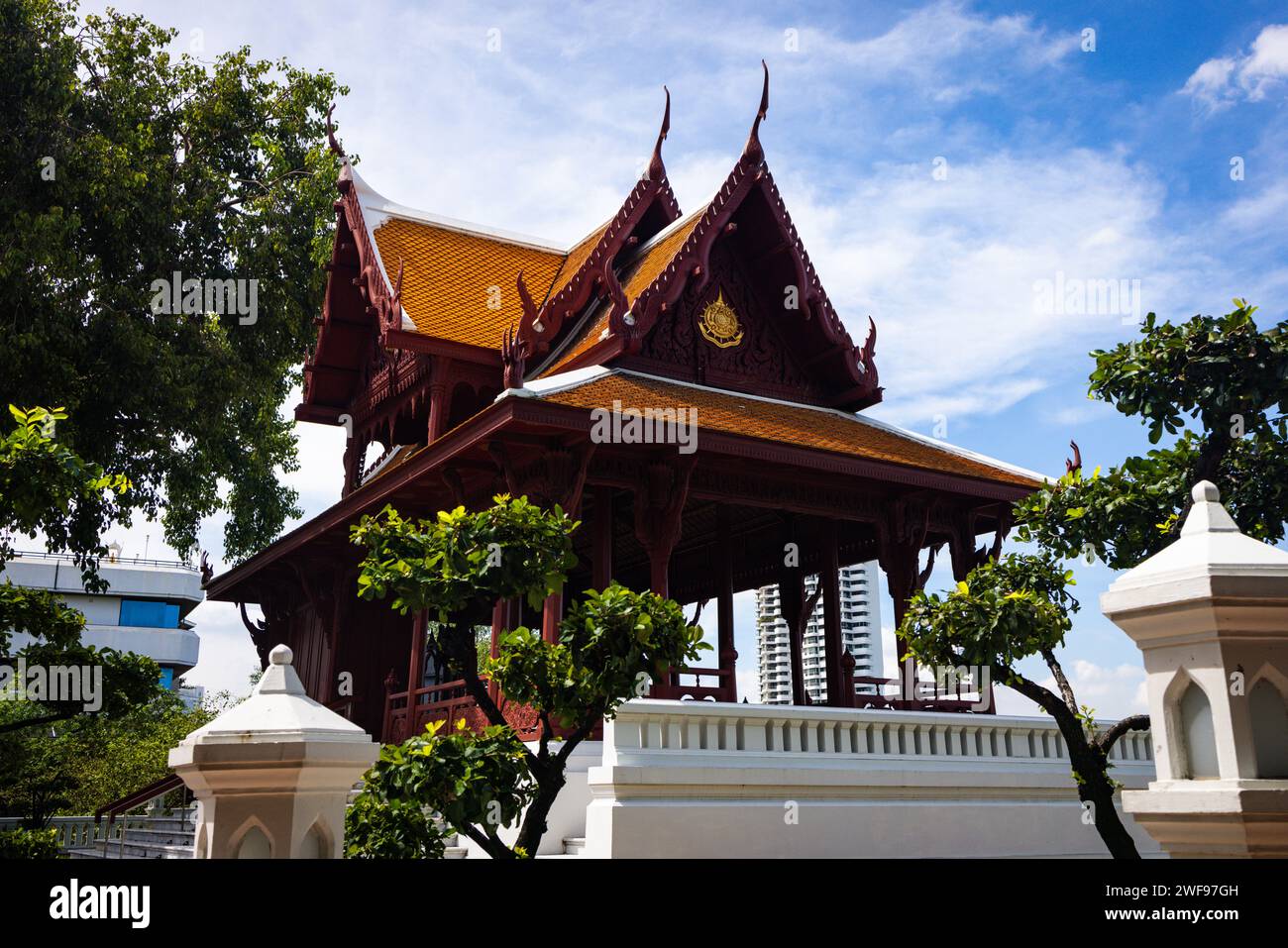 A tall wooden building stands beside a vibrant green forest, creating a ...