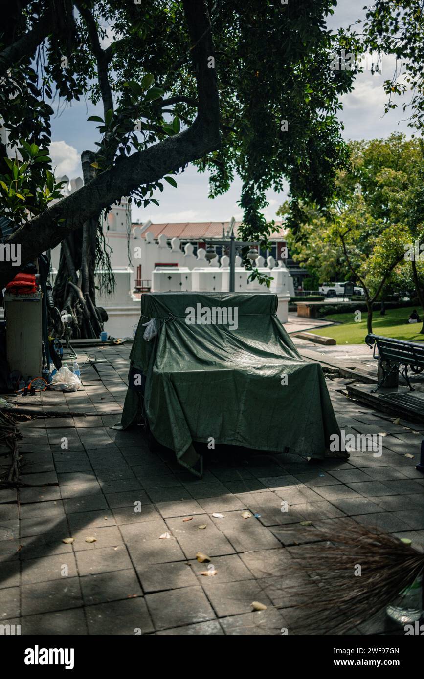 A covered bench sits peacefully next to a tall tree, offering a shady ...