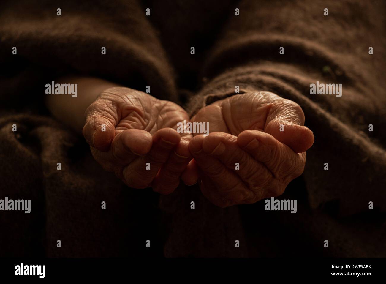 Outstretched hands of an old begging grandmother at home close-up, need ...