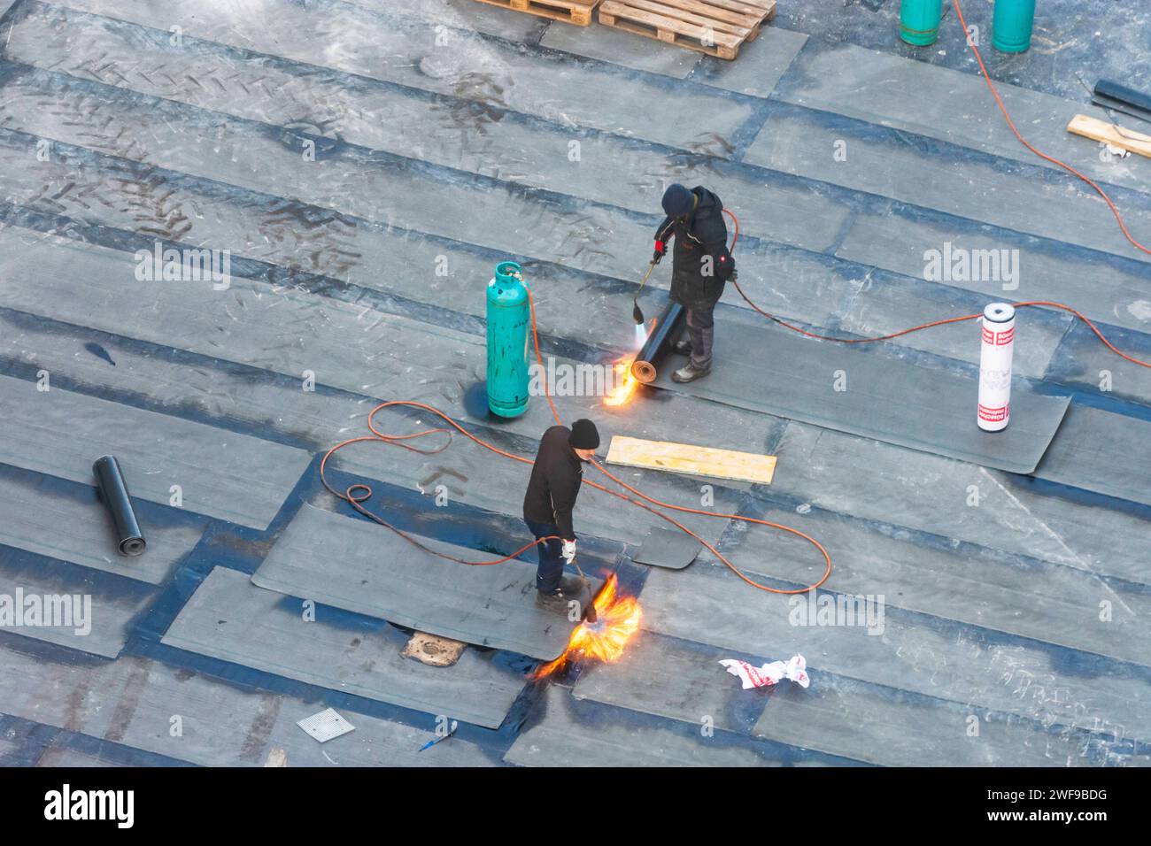 Construction workers doing waterproofing work on a building ceiling ...