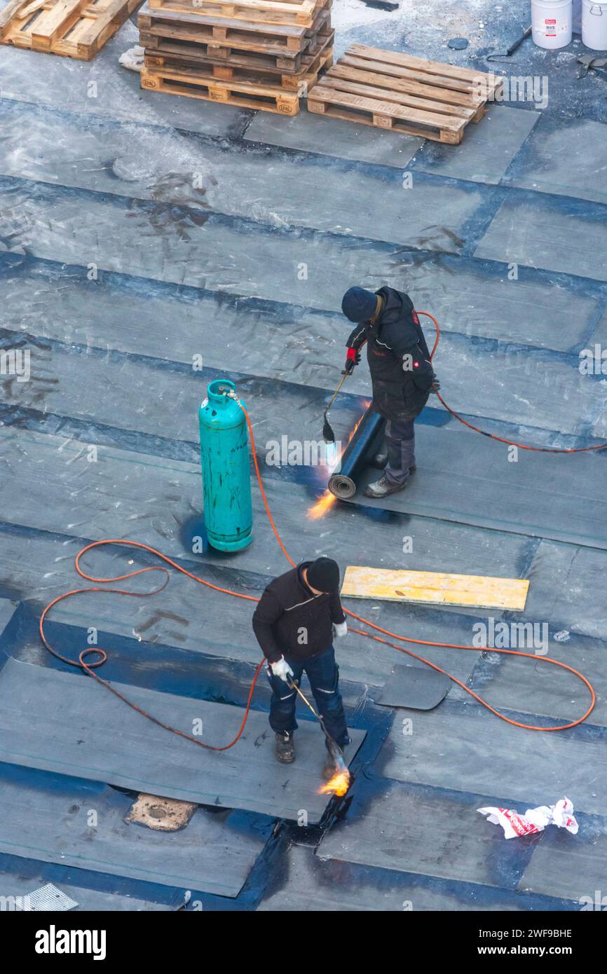 Construction workers doing waterproofing work on a building ceiling ...