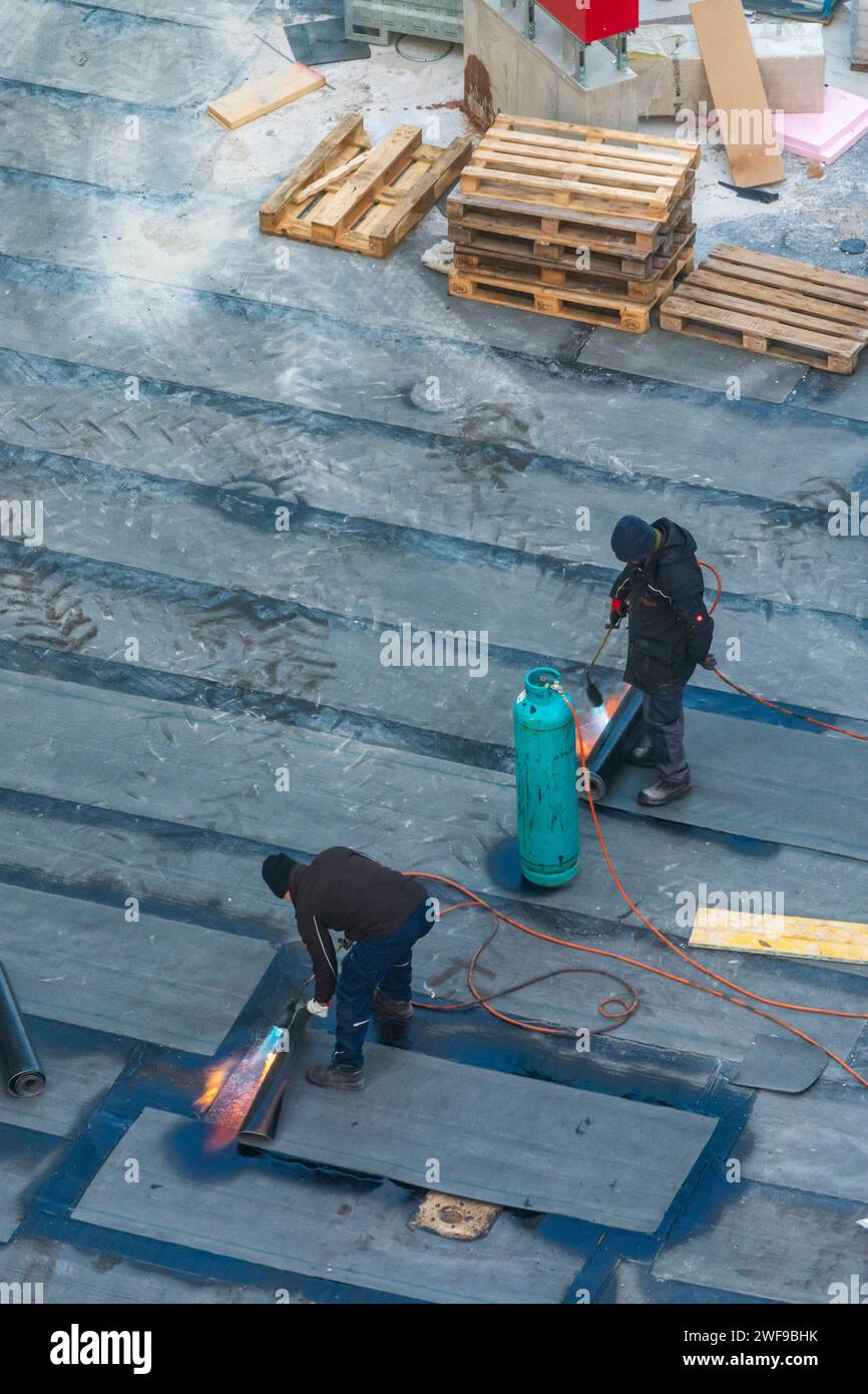 Construction workers doing waterproofing work on a building ceiling ...