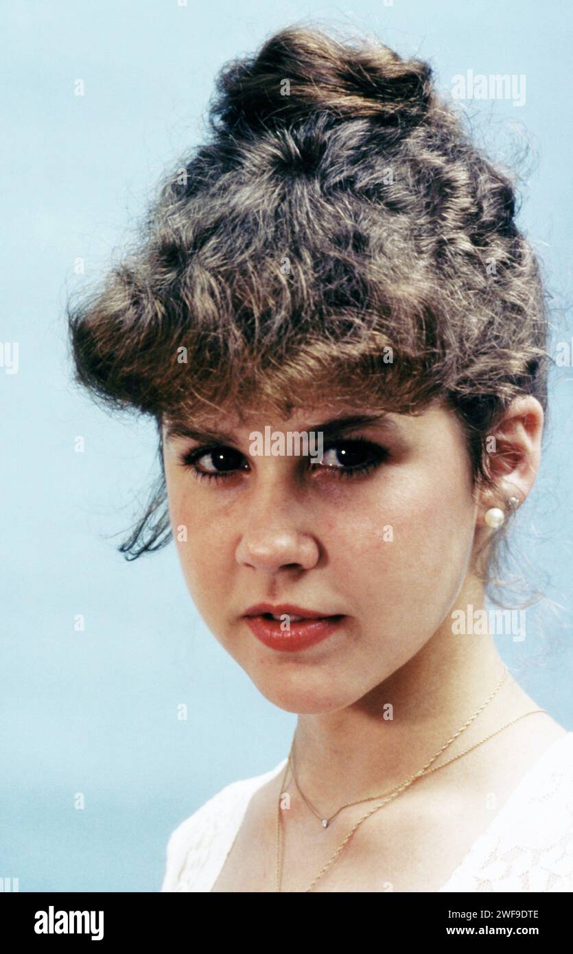 Linda Blair with curly hair pinned into updo, and wearing two gold ...