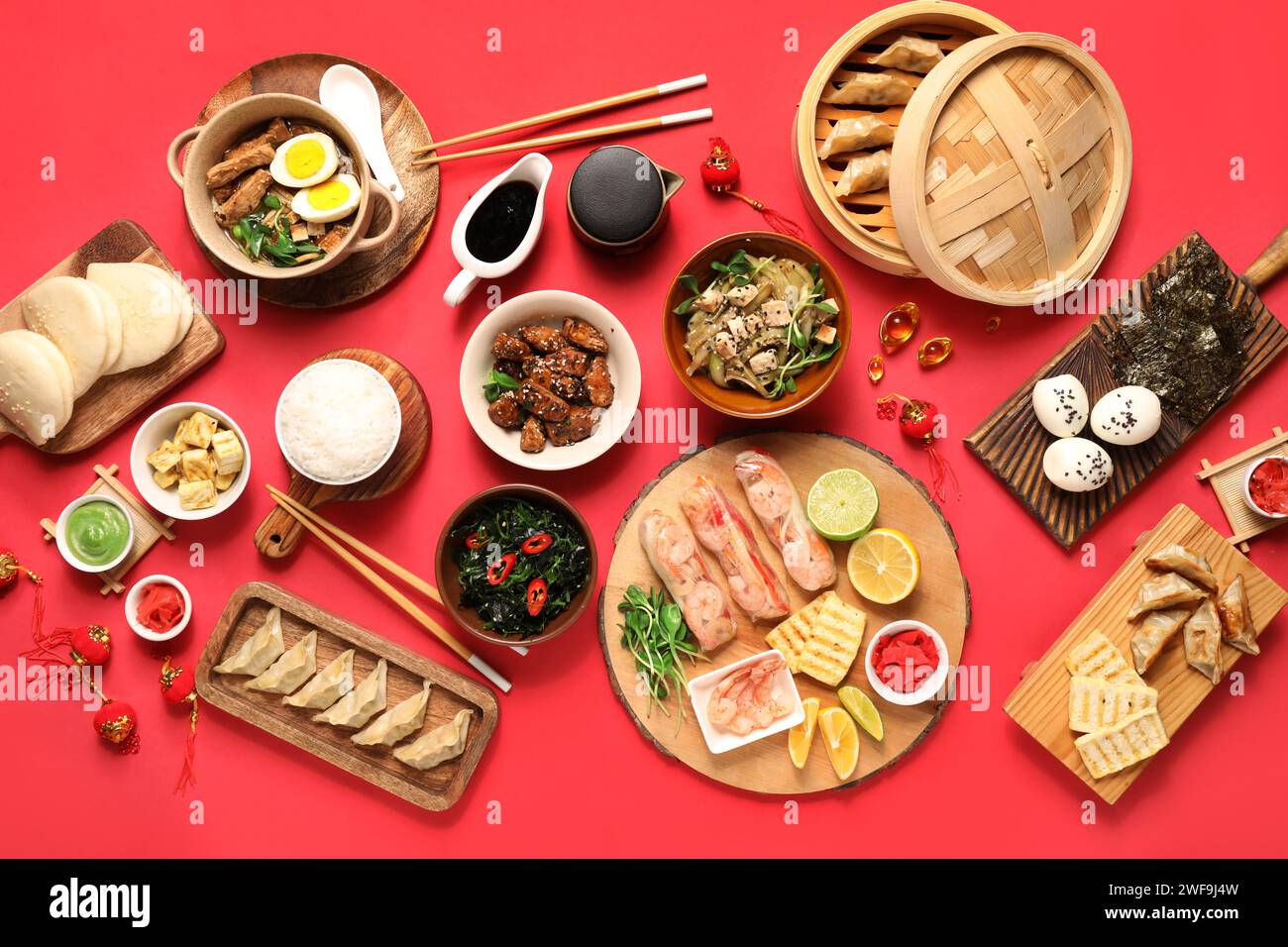 Composition with delicious Chinese dishes and decor on red background ...