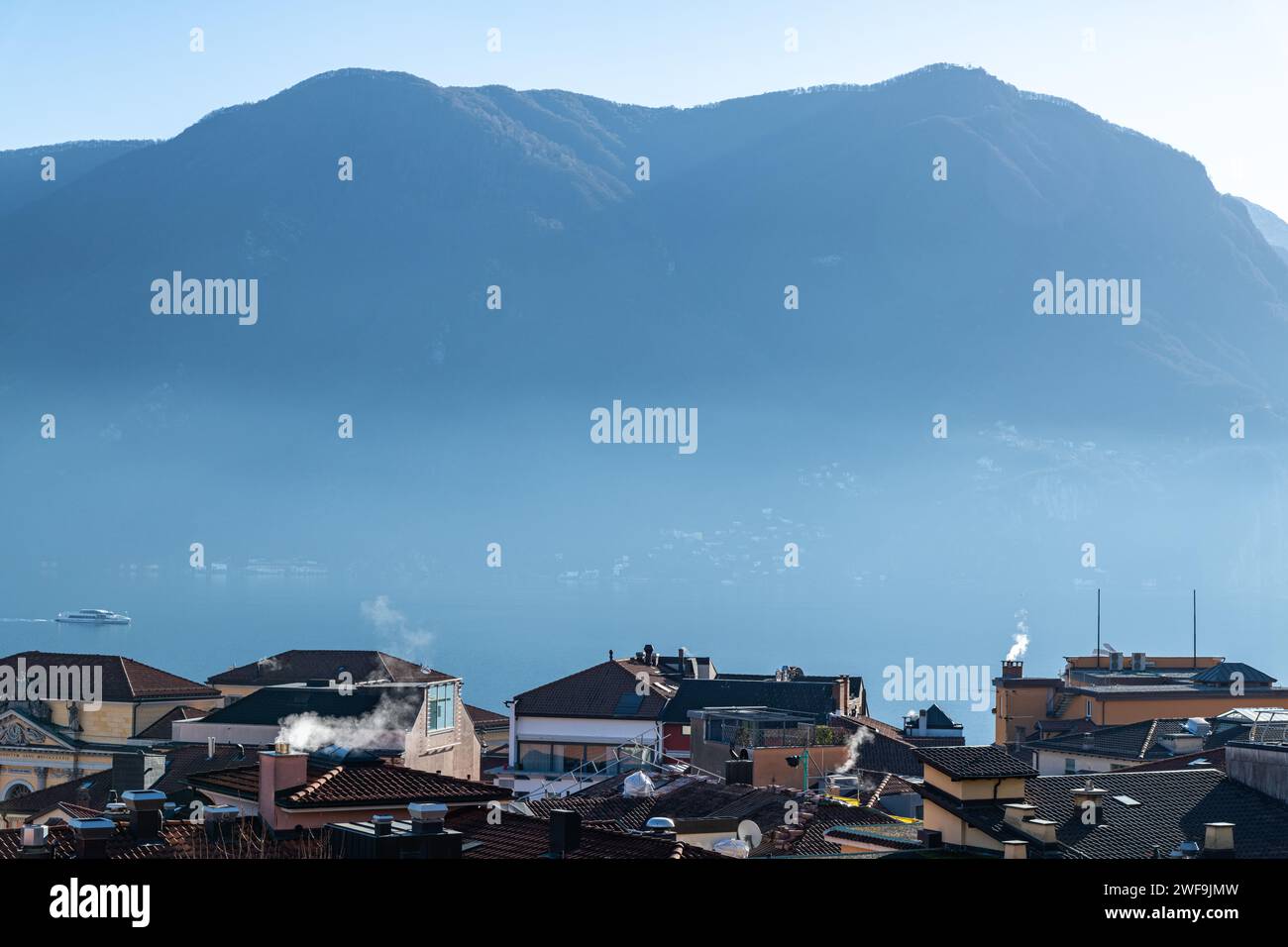 A view of the Alps mountains across the rooftops of the buildings in ...