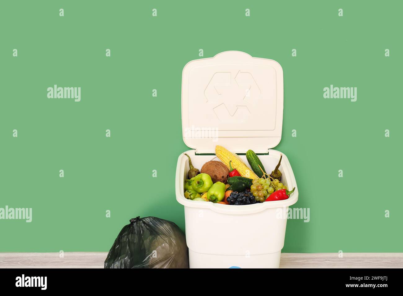 Container for trash with food waste and full garbage bag near green ...