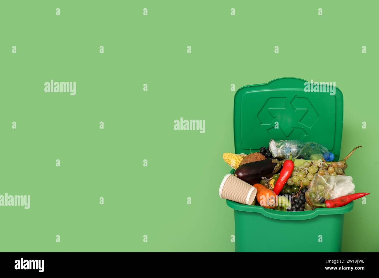 Container for garbage with food waste near green wall. Recycling ...