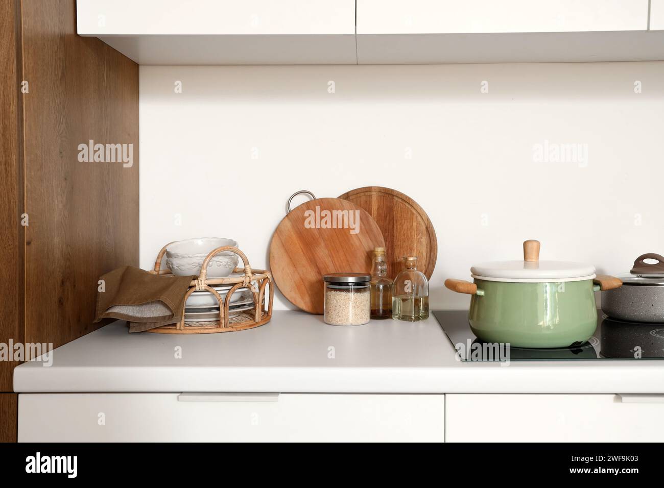 White counters with electric stove, cooking pots and utensils in modern ...