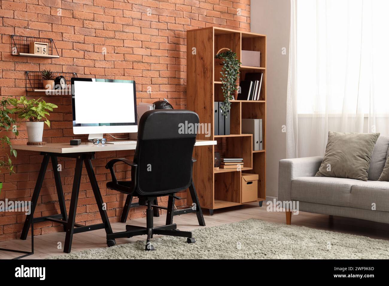 Interior of office with workplace, shelf unit and sofa Stock Photo - Alamy