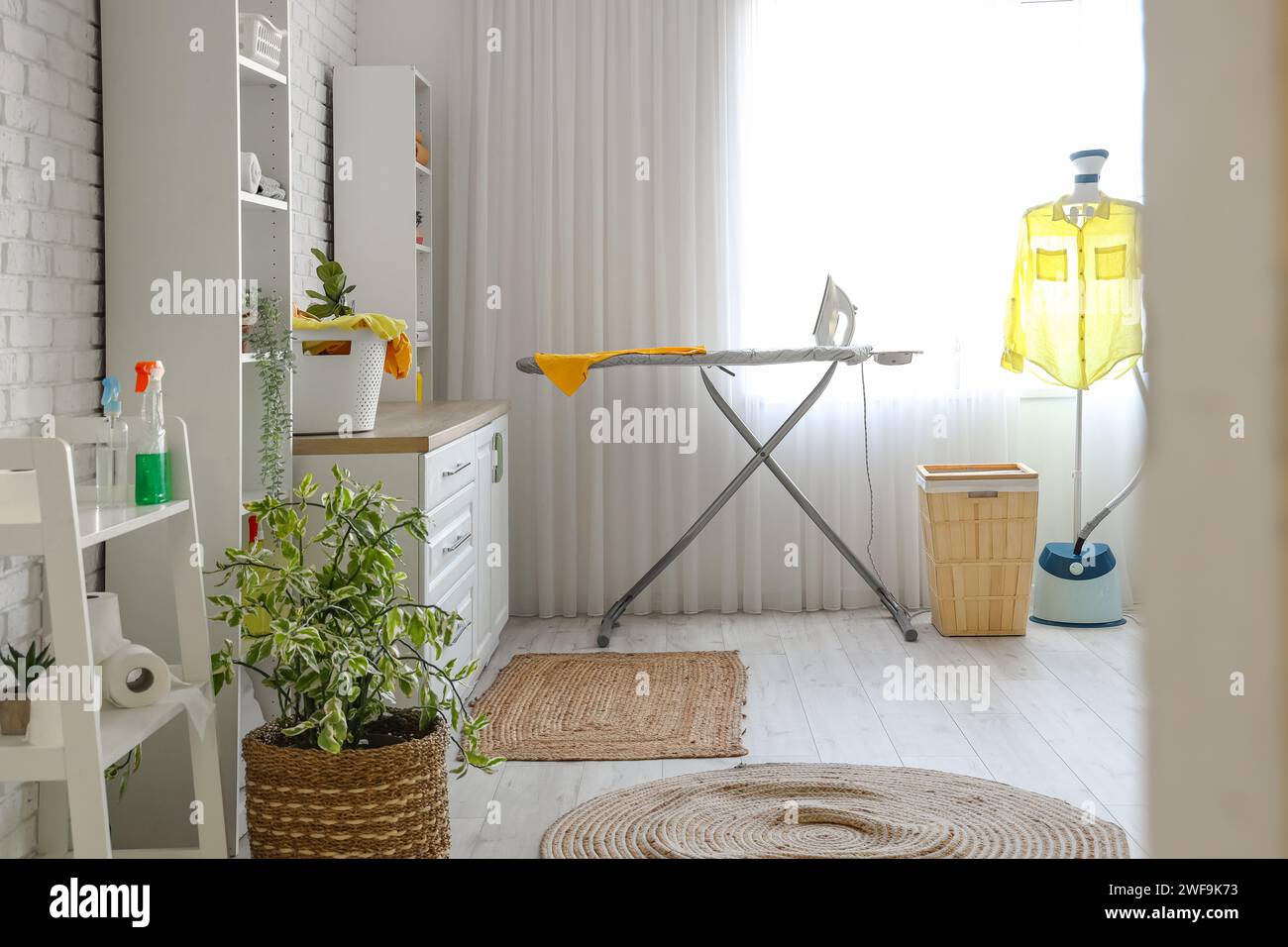 Interior of laundry room with ironing board and steamer Stock Photo - Alamy