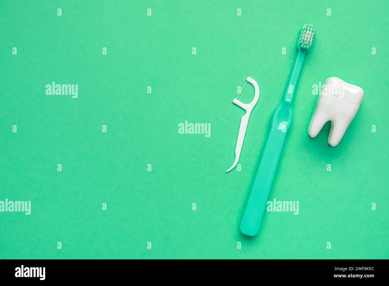 Toothbrush, tooth model and floss toothpick on green background. World ...