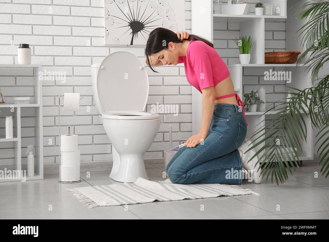 Sick young woman with pregnancy test near toilet bowl in restroom Stock ...
