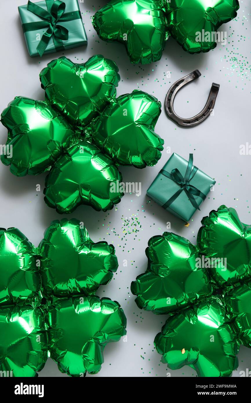 Balloons in shape of clover, gift boxes and horseshoe on grey ...