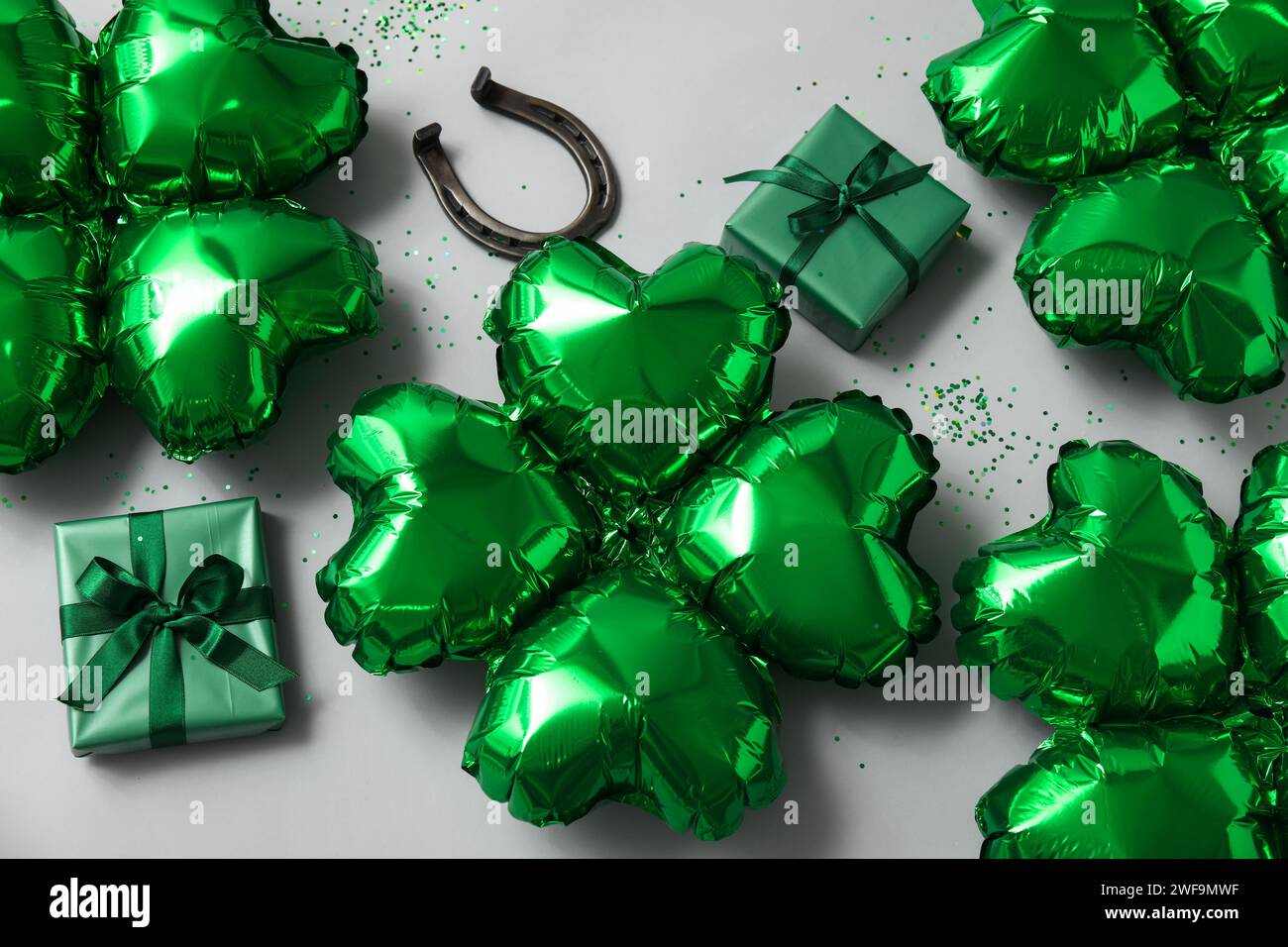 Balloons in shape of clover, gift boxes and horseshoe on grey ...
