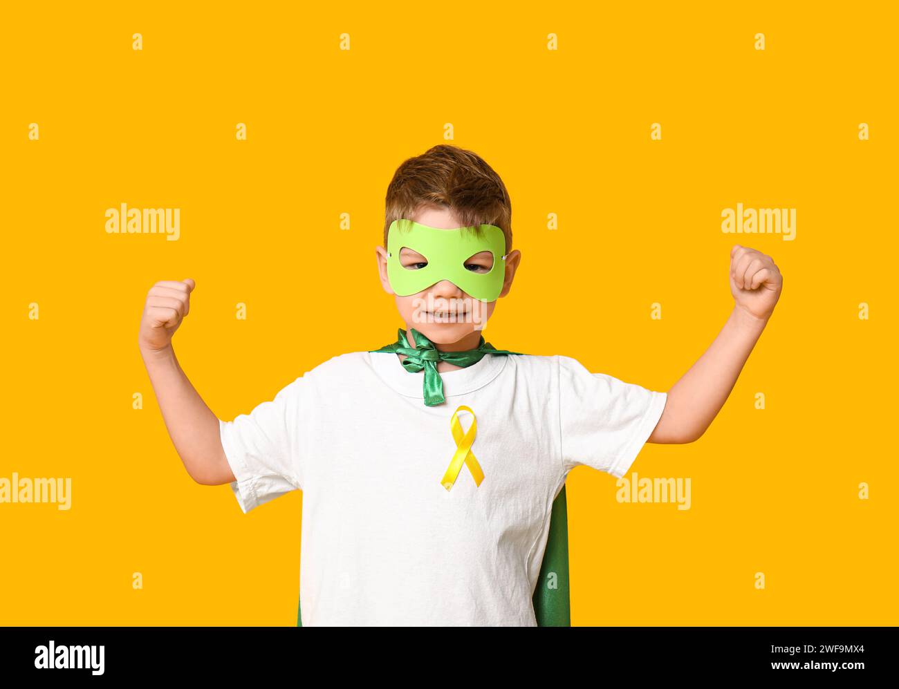 Cute little boy in superhero costume with yellow ribbon on color ...
