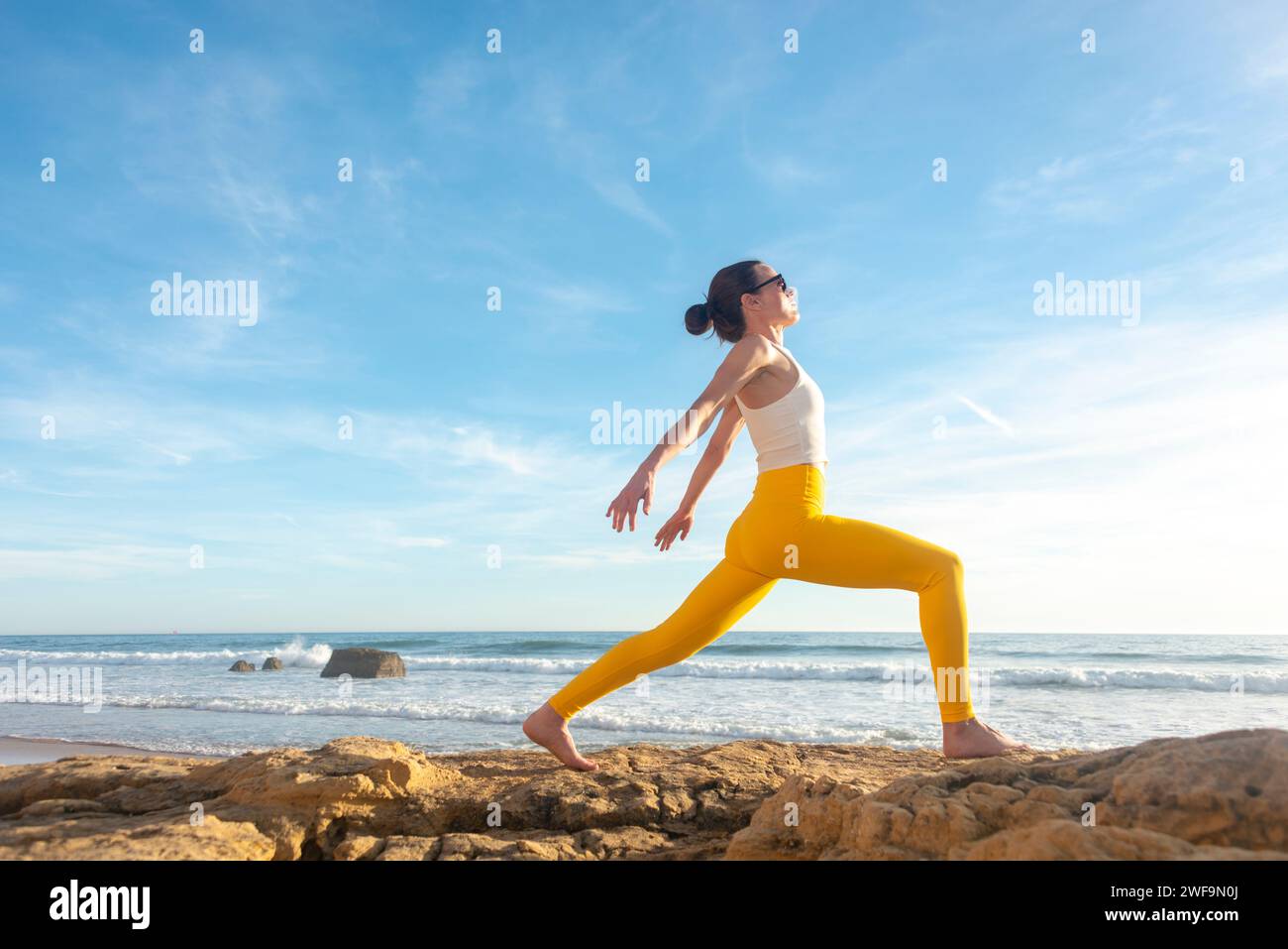 woman doing pilates stretching exercises at the beach on a rock Stock ...