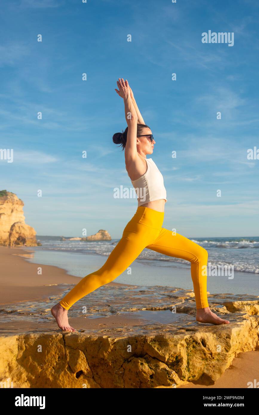 woman doing pilates stretching exercises at the beach on a rock Stock ...