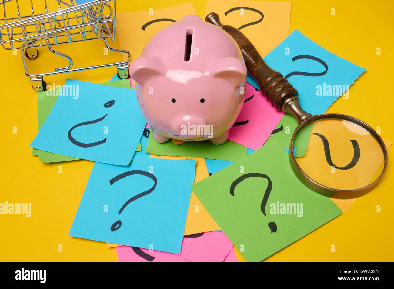 Ceramic piggy bank and stickers with drawn question marks on a yellow ...