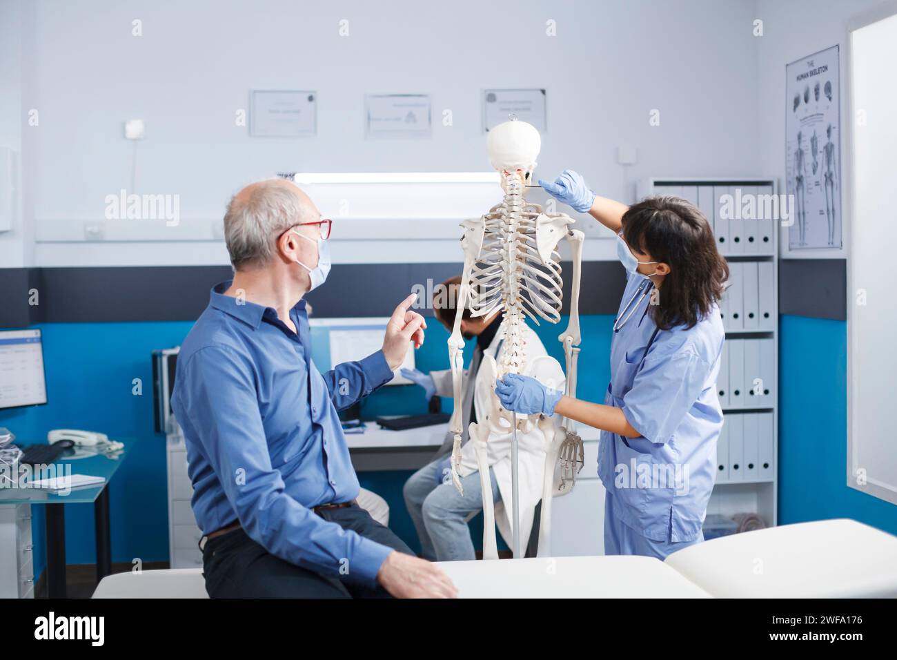 Elderly patient looking at human skeleton for orthopedic healthcare ...