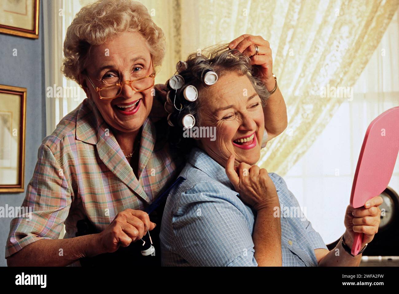 A portrait of two senior women best friends happily posing together ...