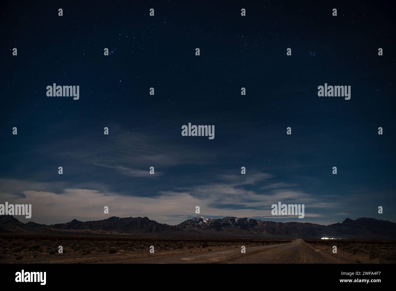 Starry night sky above a dirt road and the mountains near Death Valley ...
