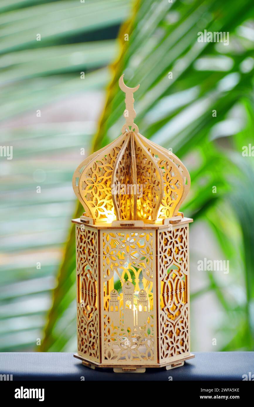 Golden shining wooden Ramadan lantern with Islamic carvings on a dark ...
