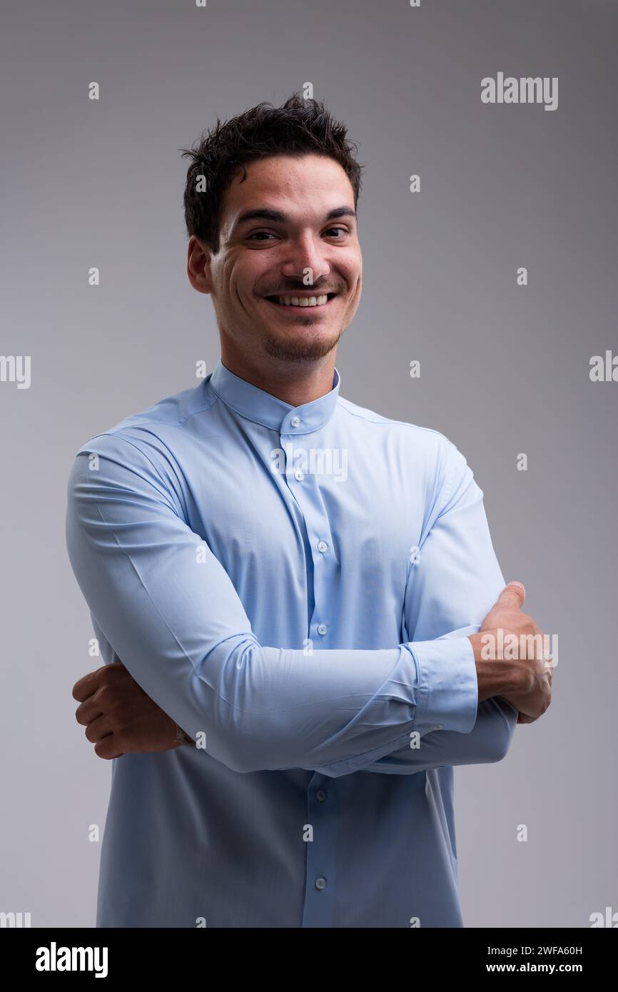 Smiling fit young man in a blue shirt shares a joyful moment, his arms ...