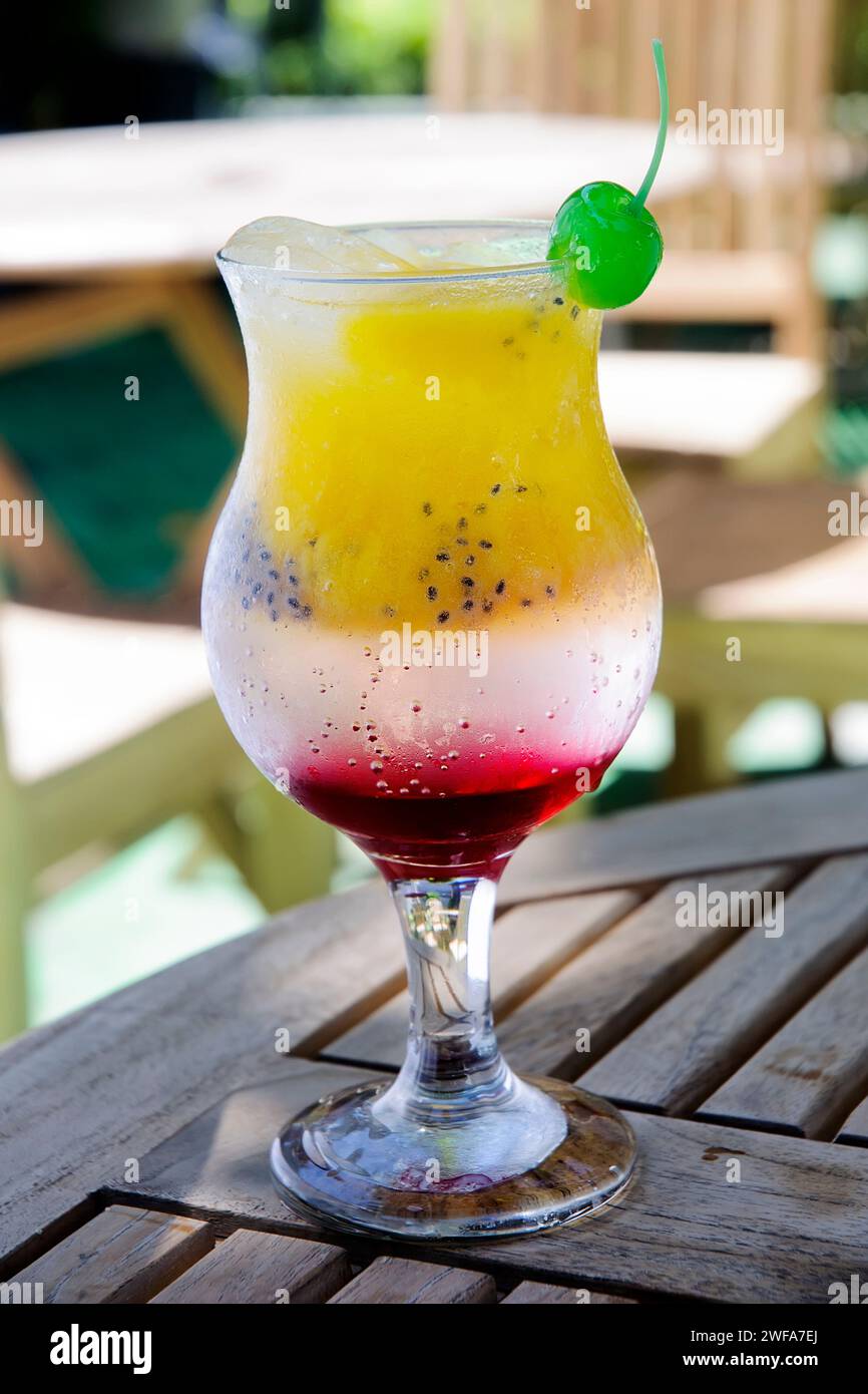 a glass of yellow mocktail served with ice, basil and cherries as ...