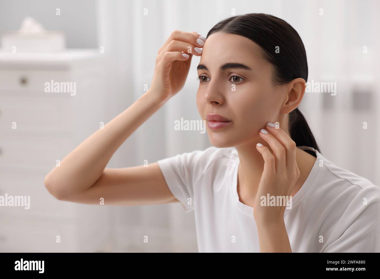 Woman with dry skin checking her face indoors Stock Photo - Alamy