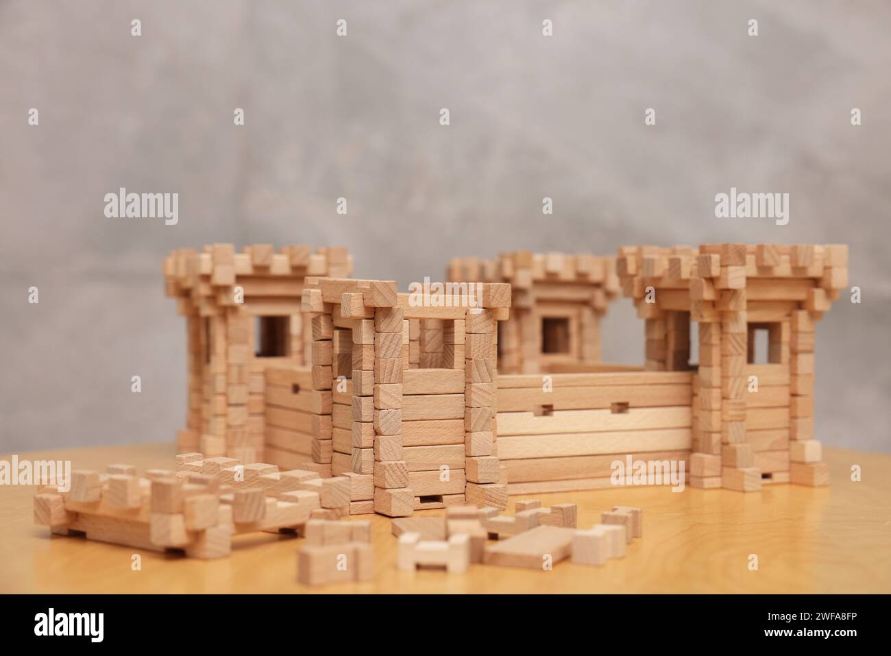 Wooden fortress and building blocks on table against grey background ...