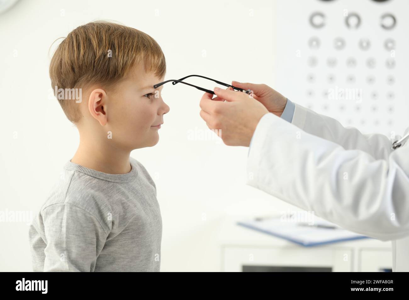 Vision testing. Ophthalmologist giving glasses to little boy indoors ...
