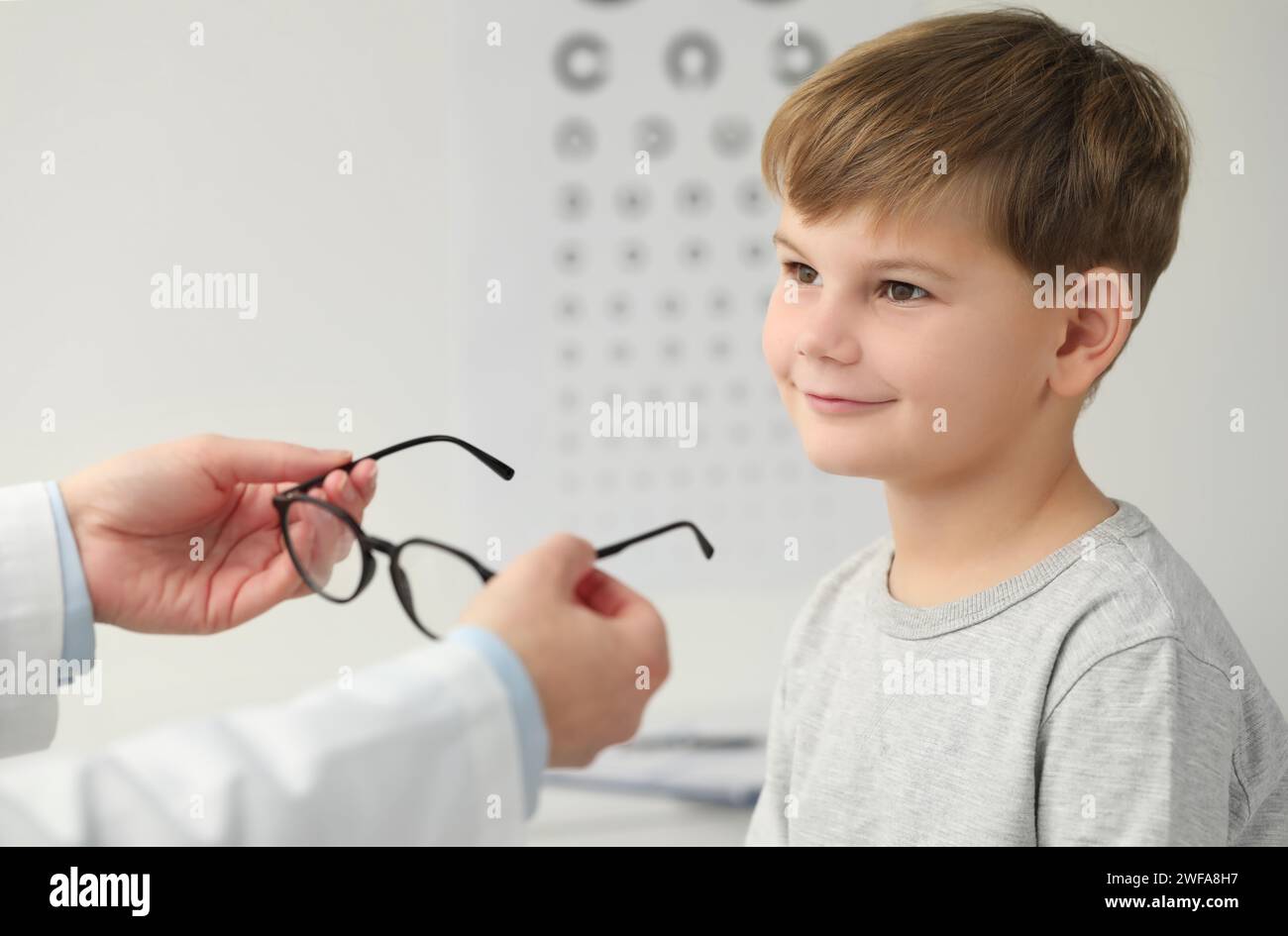 Vision testing. Ophthalmologist giving glasses to little boy indoors ...