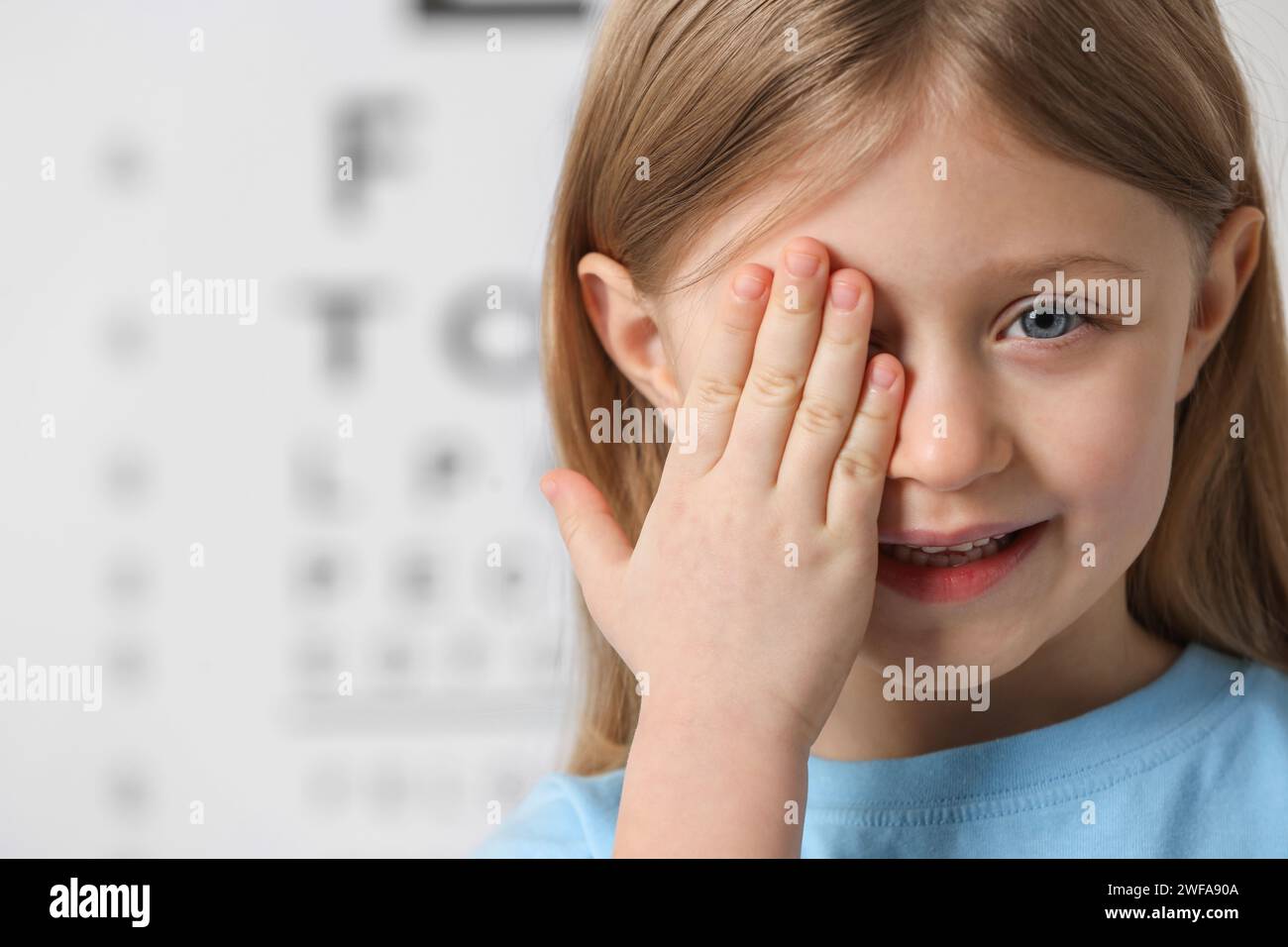 Little girl covering her eye against vision test chart Stock Photo - Alamy