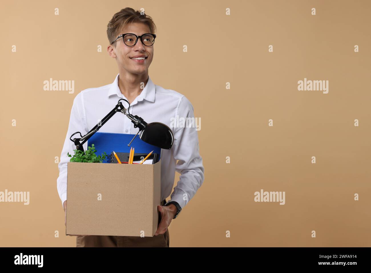 Happy unemployed young man with box of personal office belongings on ...