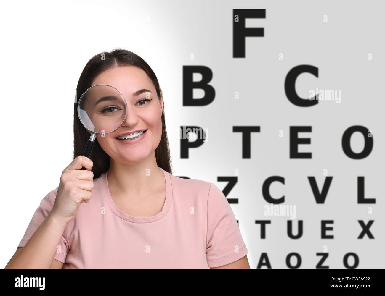 Vision test. Young woman with magnifying glass and eye chart on light ...
