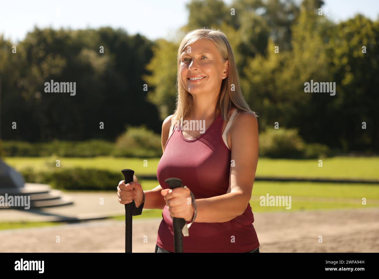 Smiling senior woman hiking with trekking poles hi-res stock ...